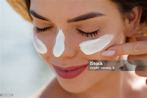 뷰티 선탠 Spf 및 스킨 케어 화장품 모델 얼굴 초상화 보습 크림을 가진 여자 피부에 자외선 차단제를 사용하는 소녀 자외선 차단제 제품 또는 그녀의 뺨에 선탠 로션 고급