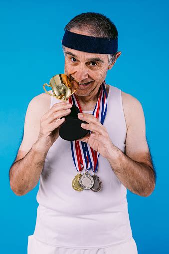 그의 팔에 태양 자국을 가진 노인 운동 선수 그의 목에 세 개의 메달을 물어 트로피를 물어 푸른 배경에 2 위 상 종류에 대한 스톡 사진 및 기타 이미지 Istock