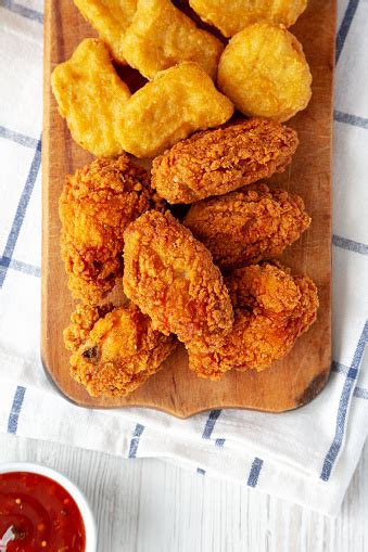 수제 바삭한 프라이드 치킨 윙과 새콤달콤한 소스를 곁들인 너겟을 소박한 나무 판에 올려놓고 위에서 봅니다 평평한 누워 평면도