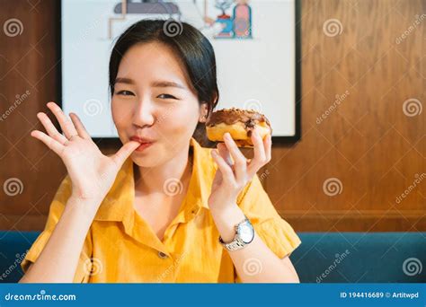 Asian Woman Is Finger Licking Good While Having A Chocolate Glazed