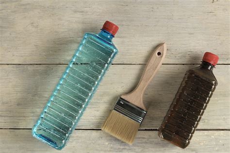 브러시는 오래된 흰색 빈티지 나무 판자 테이블에 얼룩과 용매가있는 플라스틱 병 옆에 놓여 있습니다 텍스트 또는 로고를 위한 배치입니다 가솔린에 대한 스톡 사진 및 기타