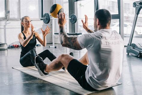 男性私人教练和运动员在健身房锻炼球