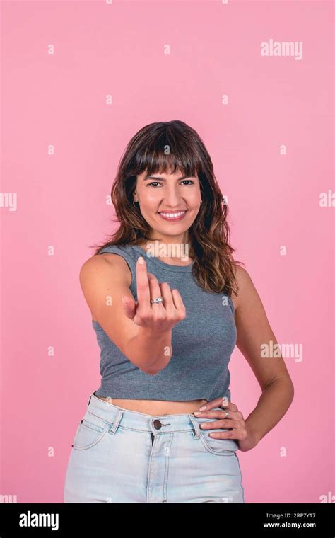Studio Portrait Of A Woman Calling With One Finger Making Beckoning