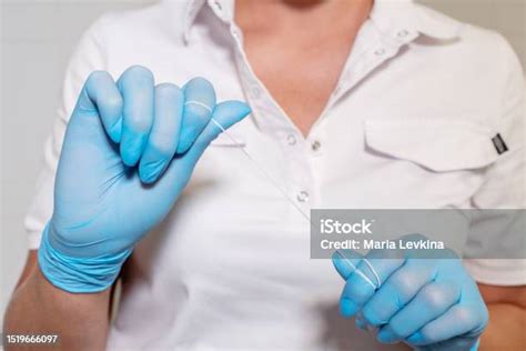 치실로 치실을 사용하는 의료용 장갑을 끼고 치과 의사의 손을 닫고 치아 관리 위생 치아 청소 루틴 및 충치 예방 여성 베니어 미소 치과 치료 및 치과 감리교에 대한 스톡