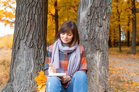 대학 공원 연구 개념입니다 가 숲에서 젊은 여자의 초상화입니다 노트북에 씁니다 세련 된 격자 무늬 코트와 스카프가을 공원에서 갈색 머리 여자 10월에 대한 스톡 사진 및