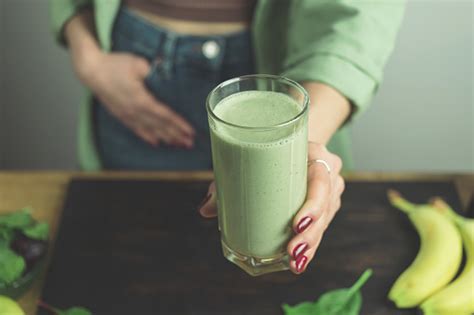 평상복 차림의 알아볼 수 없는 여성이 신선한 건강한 녹색 비건 스무디 한 잔을 들고 있습니다 바나나 시금치 사과 아보카도를