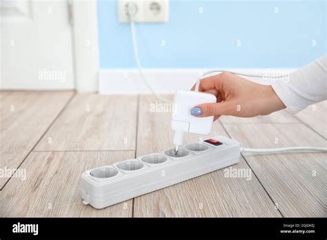 Woman Inserting Plug Into Extension Cord In Room Stock Photo Alamy