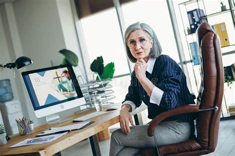 Mature Professional Woman Working At Desk In Bright Office Space