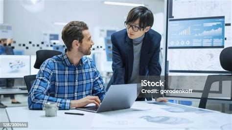 현대 공장 그의 책상에 앉아 노트북 컴퓨터에서 작업 최고 프로젝트 관리자와 이야기 그들은 메커니즘과 청사진을 분석 Cnc 작업 기계와 제조 공장 2명에 대한 스톡 사진 및