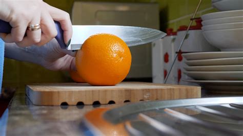 Tangan Wanita Memotong Jeruk Di Atas Meja Papan Kayu Di Dapur Foto Stok
