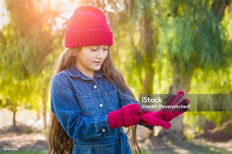 귀여운 혼혈 소녀 레드 입고 니트 모자 장갑에 야외에서 퍼 팅 옷 입기에 대한 스톡 사진 및 기타 이미지 옷 입기 겨울 계절 Istock