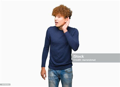 귀는 청각 소문 또는 험담을 듣고 통해 손으로 웃는 아프로 머리 젊은 잘생긴 남자 난청 개념입니다 곱슬 머리에 대한 스톡 사진