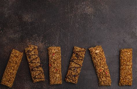 그 라 놀라 바 및 재료 건강 한 달콤한 디저트 간식입니다 견과류와 초콜릿 어두운 배경에 딸기 시리얼 뮤 즐 리 바 보기 상위 공간을 복사 합니다 건강한 생활방식에 대한