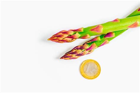 무리 신선한 녹색 아스파라거스 새싹 흰색 배경에 고립 된 유로 동전과 정상 유럽 음식 소비 시장 거래 및 비즈니스 개념 건강한