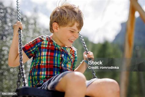 재 밌 보 체인 그네와 야외 놀이터에 동안 재미 물 뿌리지 젖은 되 고 어린이 여름 날에 스윙입니다 아이 들과 함께 활성 레저입니다 비와 함께 행복 한 우는 소년 얼굴에