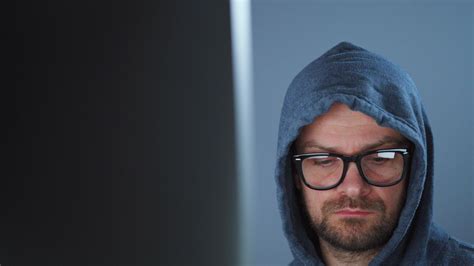 Male Hacker In The Hood And Glasses Working On A Computer In A Dark Office Room Cybercrime