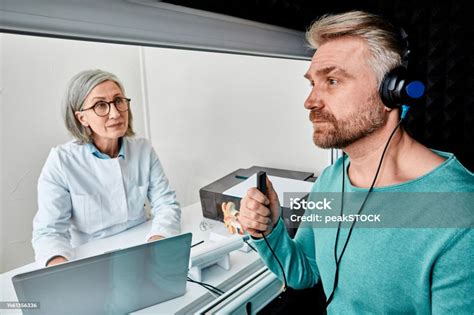 방음 청력학 부스에서 청력 테스트를 하는 동안 응답 버튼을 누르는 청력학 헤드폰을 착용한 남성 환자 청력 검사 2명에 대한 스톡 사진 및 기타 이미지 Istock