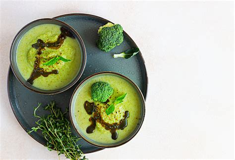 브로콜리 또는 시금치 녹색 수프와 향기로운 매운 오일을 그릇에 담습니다 비건 건강 식품 돌 배경 맨 위 보기입니다 공간을 복사합니다 브로콜리 크림수프에 대한 스톡 사진 및