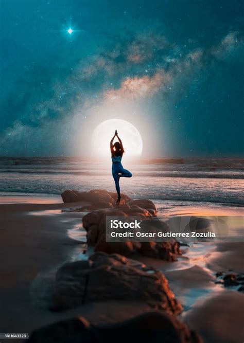 요가를 하는 한 여성의 실루엣은 밤에 해변의 바위 위에서 포즈를 취하고 달과 은하수를 배경으로 포즈를 취한다 요가에 대한 스톡 사진 및 기타 이미지 Istock