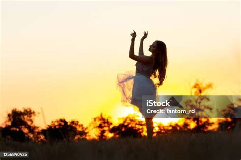 나무와 수평선에 일몰에 드레스에 아름다운 소녀의 실루엣 자연을 즐기는 긴 머리를 가진 젊은 여성의 그림 여가의 개념 감정에 대한