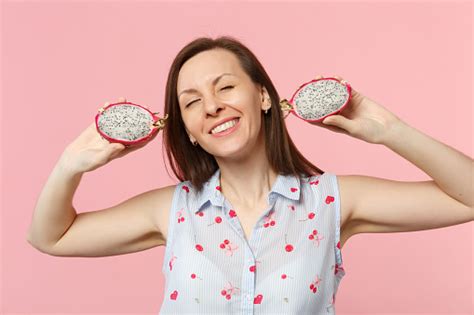 웃는 젊은 여자는 신선한 잘 익은 피타 하 야 핑크 파스텔 벽 배경에 고립 된 용 과일의 Halfs를 들고 눈을 유지 사람들은 생생한 라이프 스타일 휴식 휴가 개념입니다