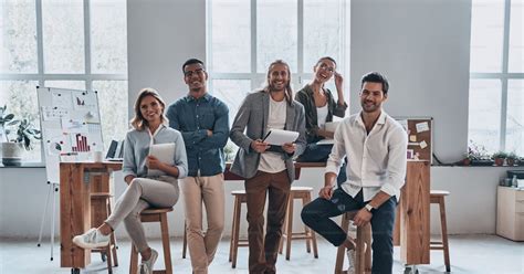 스마트 캐주얼 옷을 입은 젊은 현대인들이 창의적인 사무실에 서서 웃고 카메라를 바라보고 있다 사진 Unsplash의 남자 이미지