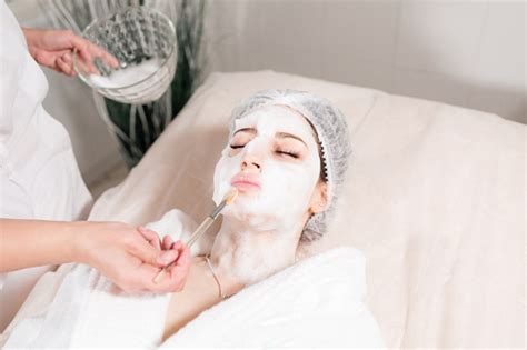 뷰티 살롱에서 트리 트 먼 트를 받는 젊은 예쁜 여자 소파에 누워 사무실 미용사에 젊은 아름 다운 검은 머리 여자 얼굴 클렌징 폼을 사용 하 여입니다 건강 진단에 대한 스톡