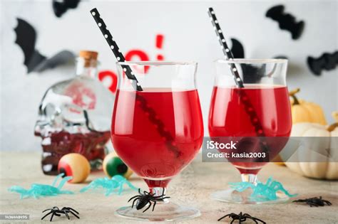 할로윈 피 묻은 칵테일 할로윈을 위한 두 개의 피 묻은 칵테일 유리 잔과 밝은 배경에 병 형태의 두개골 사탕 눈 박쥐 거미 및 호박과 함께 할로윈 파티를위한 장식 개념 마실