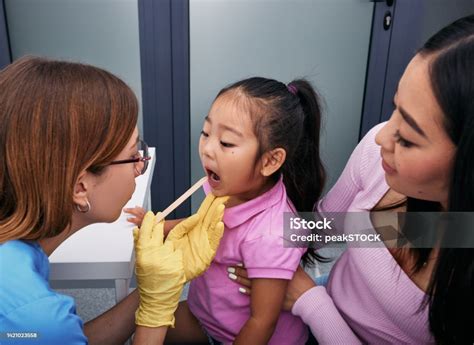 한국의 어린 소녀 목을 검사하기 위해 검사 주걱을 사용하는 의사 소아과 의사 약속에서 어머니와 함께 귀여운 여자 아이 아이에 대한 스톡 사진 및 기타 이미지 Istock