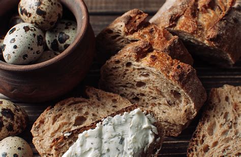 어두운 메밀 빵은 소박한 스타일의 점토 접시에 메추라기 계란 근처 나무 테이블에 잘라 허브와 코티지 치즈와 함께 확산된다 간식과 아침 식사 개념 깨에 대한 스톡 사진 및