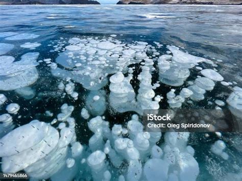 얼어 붙은 호수에 하얀 거품과 균열이있는 겨울 얼음의 자연스러운 질감 얼어붙은 바이칼 호수 표면의 얼음과 균열의 추상적인 배경