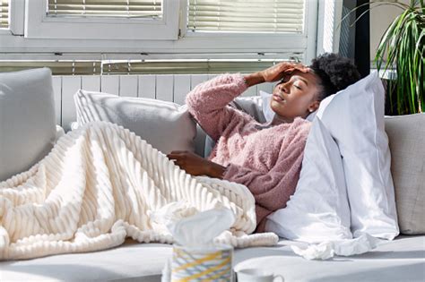 아픈 여자독감여자는 감기에 걸렸습니다 조직으로 재채기 두통 바이러스 의약품 젊은 여자 감염 에 감기 불고 그녀의 코 에 손수건 소파에 앉아 두통을 가진 아픈 여자 감기와