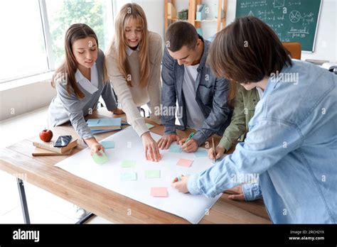 Group Of Teenage Babes Performing Task At Table In Classroom Stock Photo Alamy