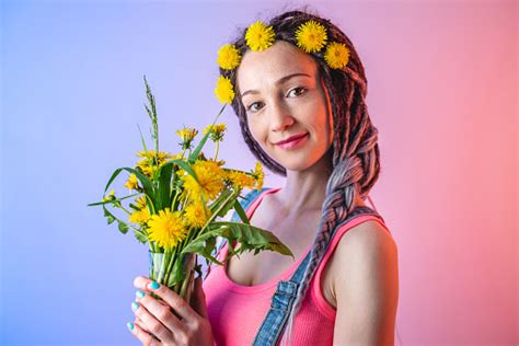 공포에 질린 젊은 행복한 여성이 파란색과 분홍색 배경에 노란색 초원 꽃의 아름다운 꽃다발을 들고있다 밝은 여름 분위기의 개념 귀여운에 대한 스톡 사진 및 기타 이미지