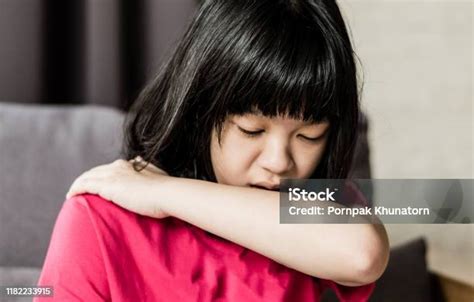 대기 오염에서 알레르기로 기침 하는 아시아 여자 아이 아시아 아이는 아픈 때 기침에서 확산 바이러스 세균의 수를 줄이기 위해 그녀의 입을 커버하기 위해 그녀의 팔꿈치와 팔을