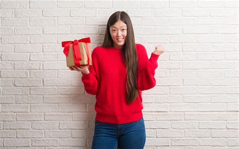 젊은 중국 여자 자랑 비명과 승리와 성공을 매우 흥분된 하 고 축 하 선물을 들고 벽돌 벽에 환호 하는 감정 감정에 대한 스톡 사진 및 기타 이미지 Istock