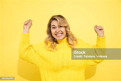 고립 된 노란색 벽 배경 에 노란색 스웨터를 입고 아름다운 귀여운 금발 머리 젊은 금발 의 여자는 미소와 함께 승리를 축하 흥분 성공 팔을 제기 승자 컨셉 25 29세에