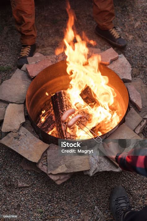 캠프 파이어 위에 소시지를 굽고 캠프는 토스트 포크에 소시지를 구이 화재 장소 친구 관광객은 불꽃 근처에 앉아있다 계절에 대한 스톡 사진 및 기타 이미지 Istock