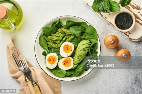 아보카도 아스파라거스 검은 참깨와 가벼운 슬레이트 돌 또는 콘크리트 배경에 접시에 시금치구를 구겨진 신선한 야채 샐러드 그릇에 균형 잡힌 점심 맨 위 보기입니다 모의 개념에
