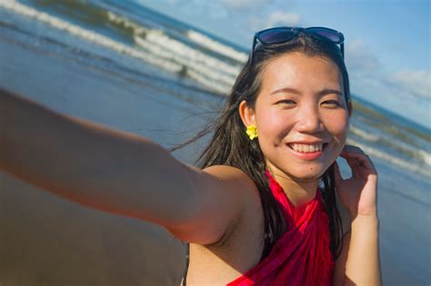 젊은 행복하고 매력적인 아시아 중국 여성 사롱 휴가및 라이프 스타일 개념에서 열대 해변에서 여름 휴가를 즐기는 휴대 전화로 소셜