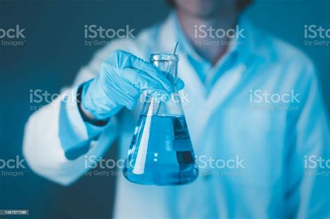 과학자는 화학 과학 실험실에서 파란색 샘플 화학 물질로 채워진 교반 막대가 있는 삼각 플라스크를 손에 들고 있습니다 의학 연구의