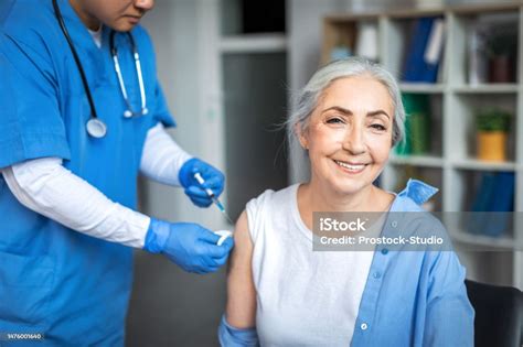 밀레니엄 남자 의사는 클리닉 사무실 내부에서 웃는 노인 여성 환자에게 주사를 만듭니다 35 39세에 대한 스톡 사진 및 기타 이미지 35 39세 60 64세