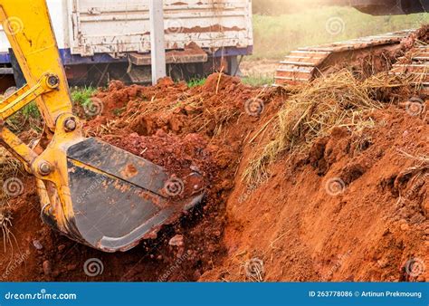 Dirt Metal Bucket Of Backhoe After Digging Soil Backhoe Parked Near Truck With Golden Sunset