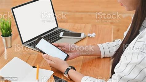 작업 용 책상에 흰색 빈 스마트 폰을 들고 사용하는 동안 젊은 창조적 인 여성의 클로즈업 이미지 공란에 대한 스톡 사진 및 기타