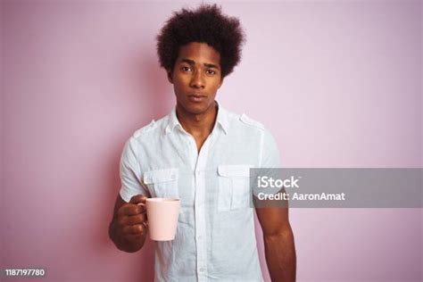 젊은 아프리카 계 미국인 남자 마시는 커피 한 잔 위에 서 고립 된 분홍색 배경 에 자신감 있는 표정으로 스마트 얼굴 생각 심각한 커피 마실 것에 대한 스톡 사진 및 기타