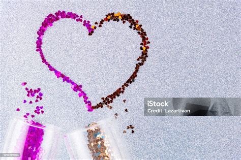 여러 가지 빛깔의 반짝이로 만든 하트 모양 궁극의 회색 반짝이 배경 위에 하트 모양의 색종이가 튀어나온 샴페인 안경 2장 발렌타인 데이 컨셉 공간을 복사합니다 위쪽 보기 2