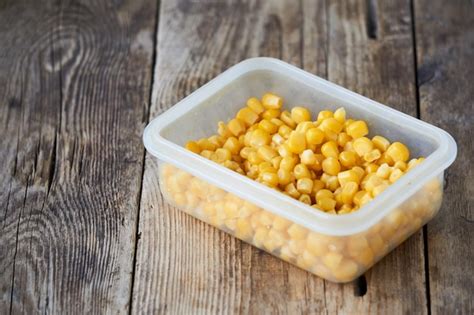 Premium Photo Canned Corn In A Plastic Container On A Wooden Table