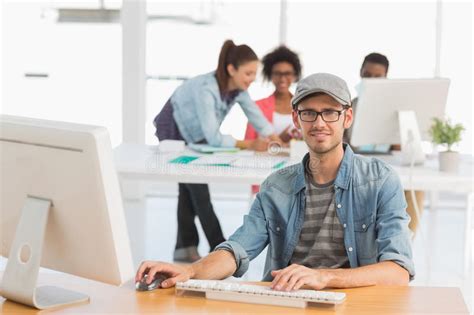 Вскользь мужской художник используя компьютер с коллегами в предпосылке Стоковое Изображение