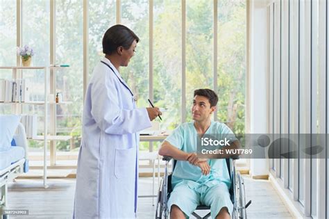 의사가 병원에서 휠체어에 앉아 있는 환자에게 환자의 질병을 진단하고 있고 환자가 휠체어를 타고 있고 의사가 진단을 내리고 의사와 환자 간의 대화 25 29세에 대한 스톡