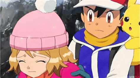 Two People Standing Next To Each Other In Front Of Snow Covered Trees With Pokemon Hats On